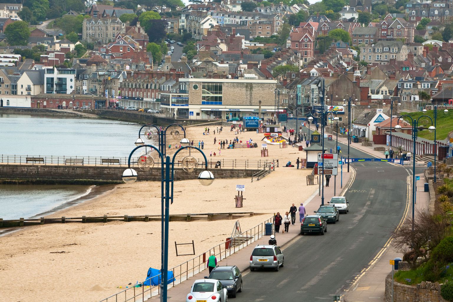 Family followed on Swanage Beach by man in bright orange high vis top
